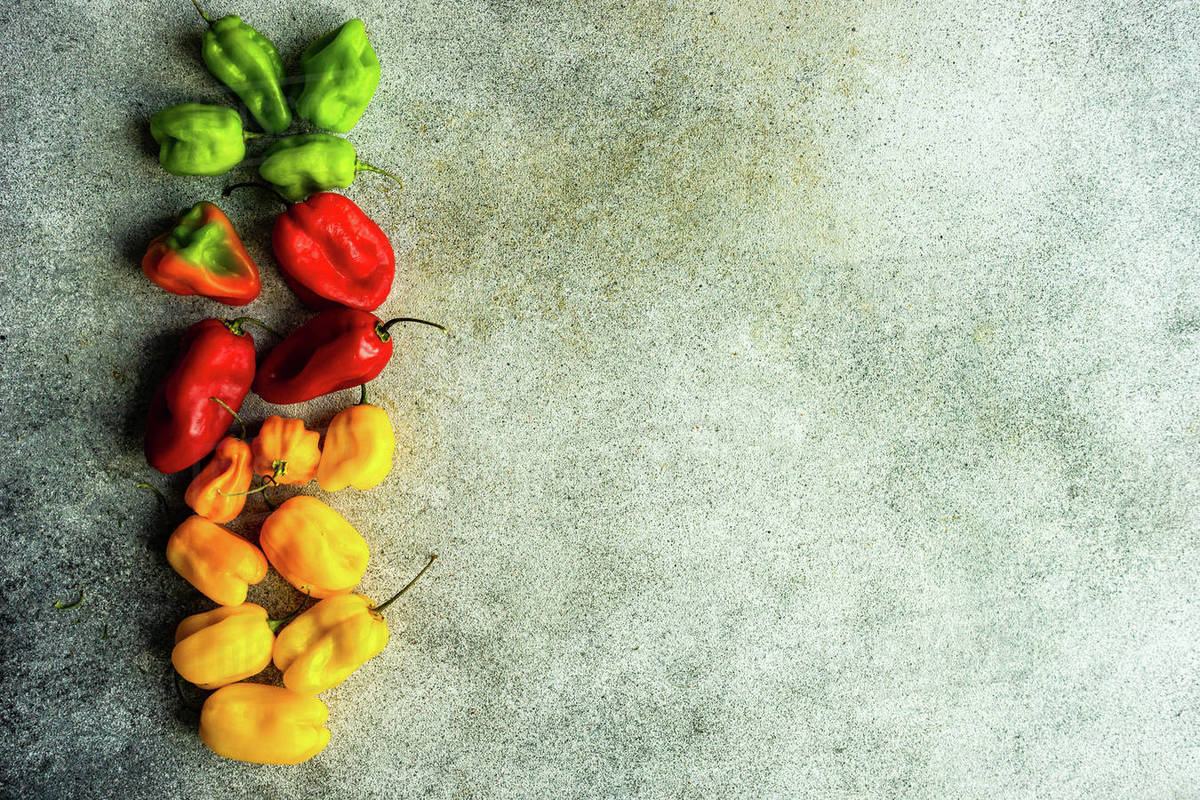 Overhead view of assorted red, green and yellow chilli peppers in a row ...