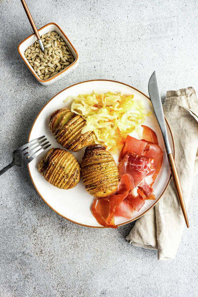 Overhead view of a plate of Hasselback potatoes with fermented cabbage ...