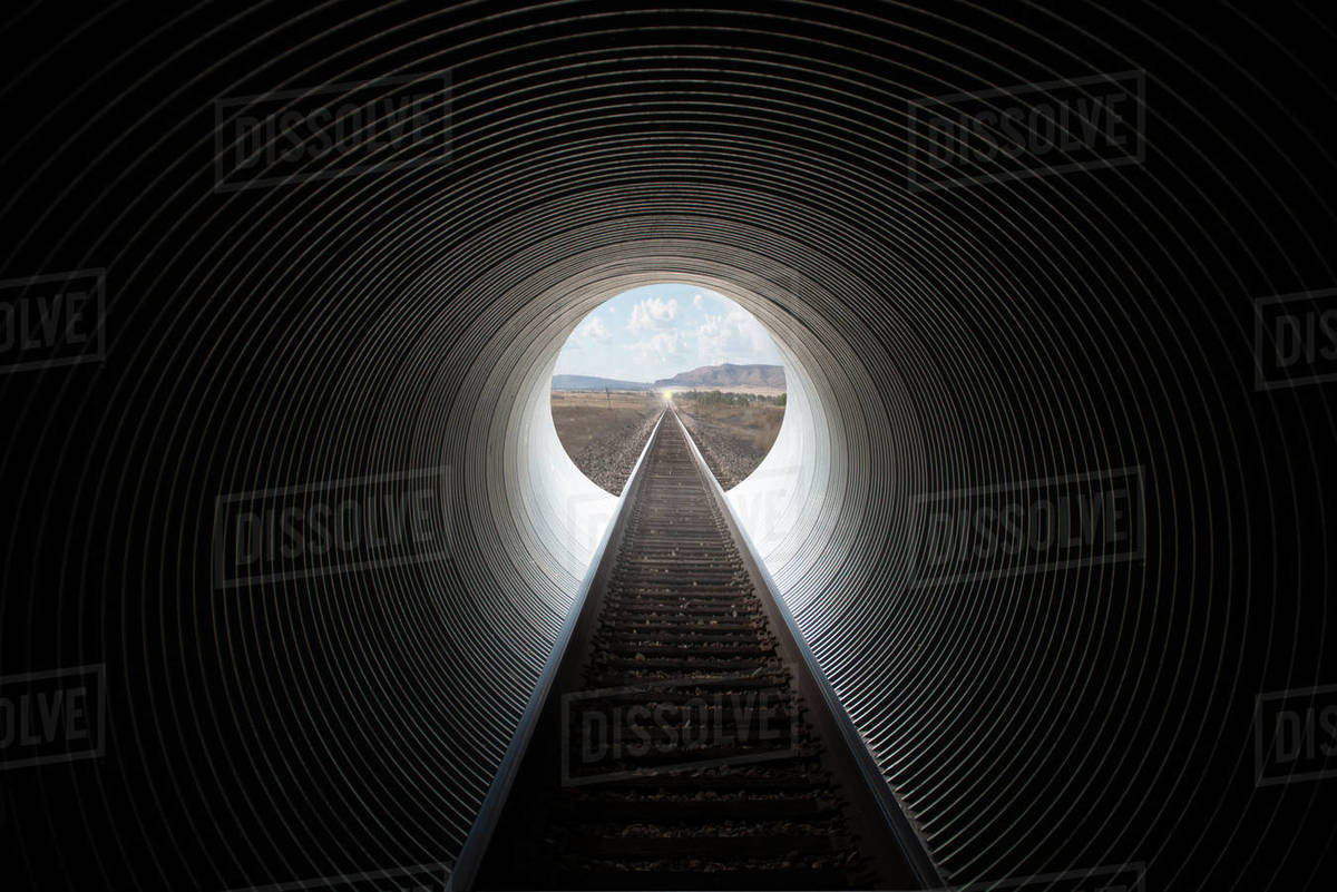 View of a train track through an empty Tunnel with a train approaching ...