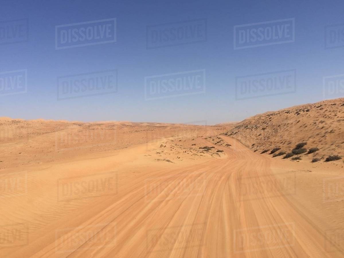 Tyre tracks through the sand dunes in desert landscape at sunset ...