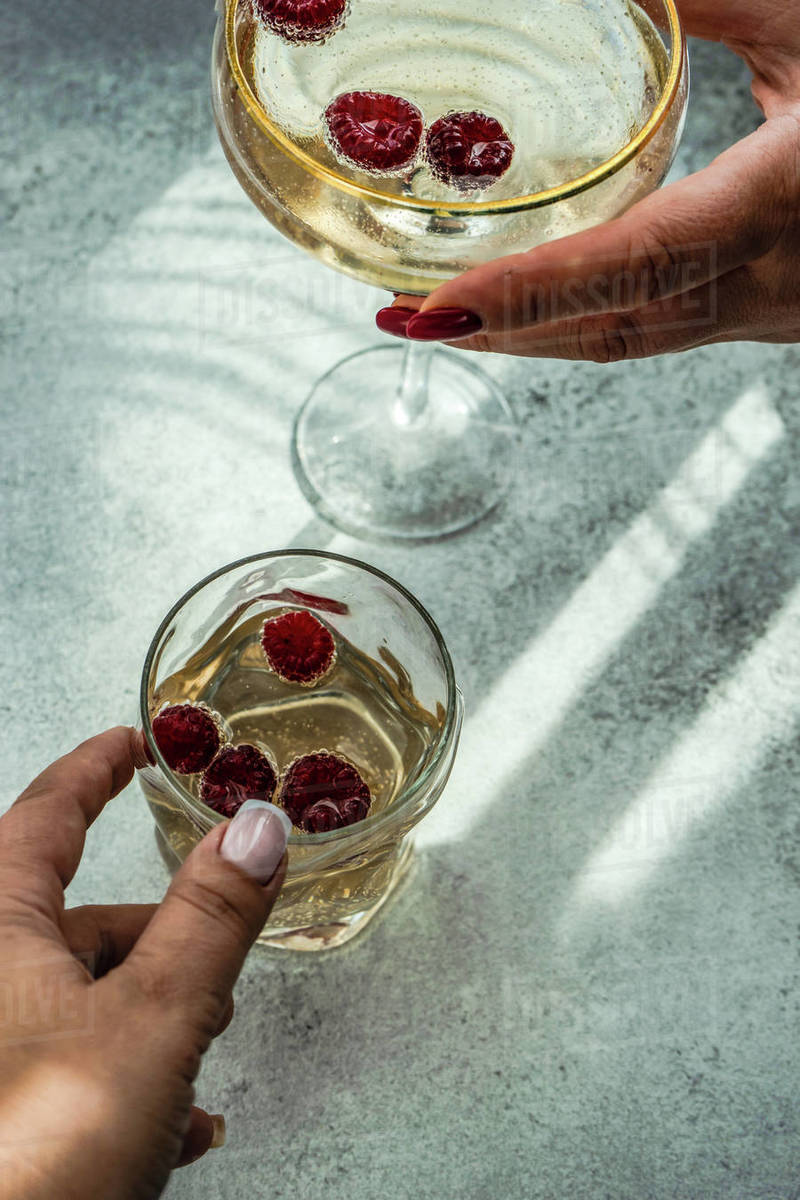 Overhead view of two women drinking glasses of champagne and cocktails ...