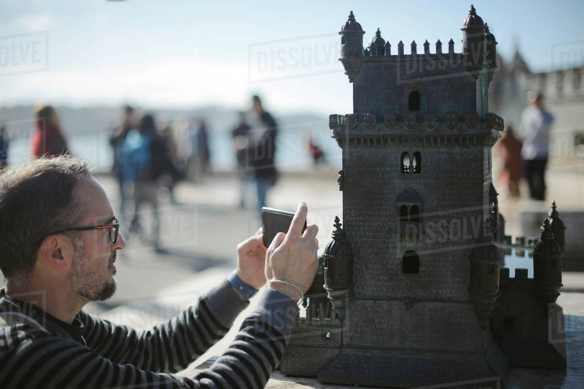 Man photographing a sculpture of Torre de Belem with his mobile phone ...