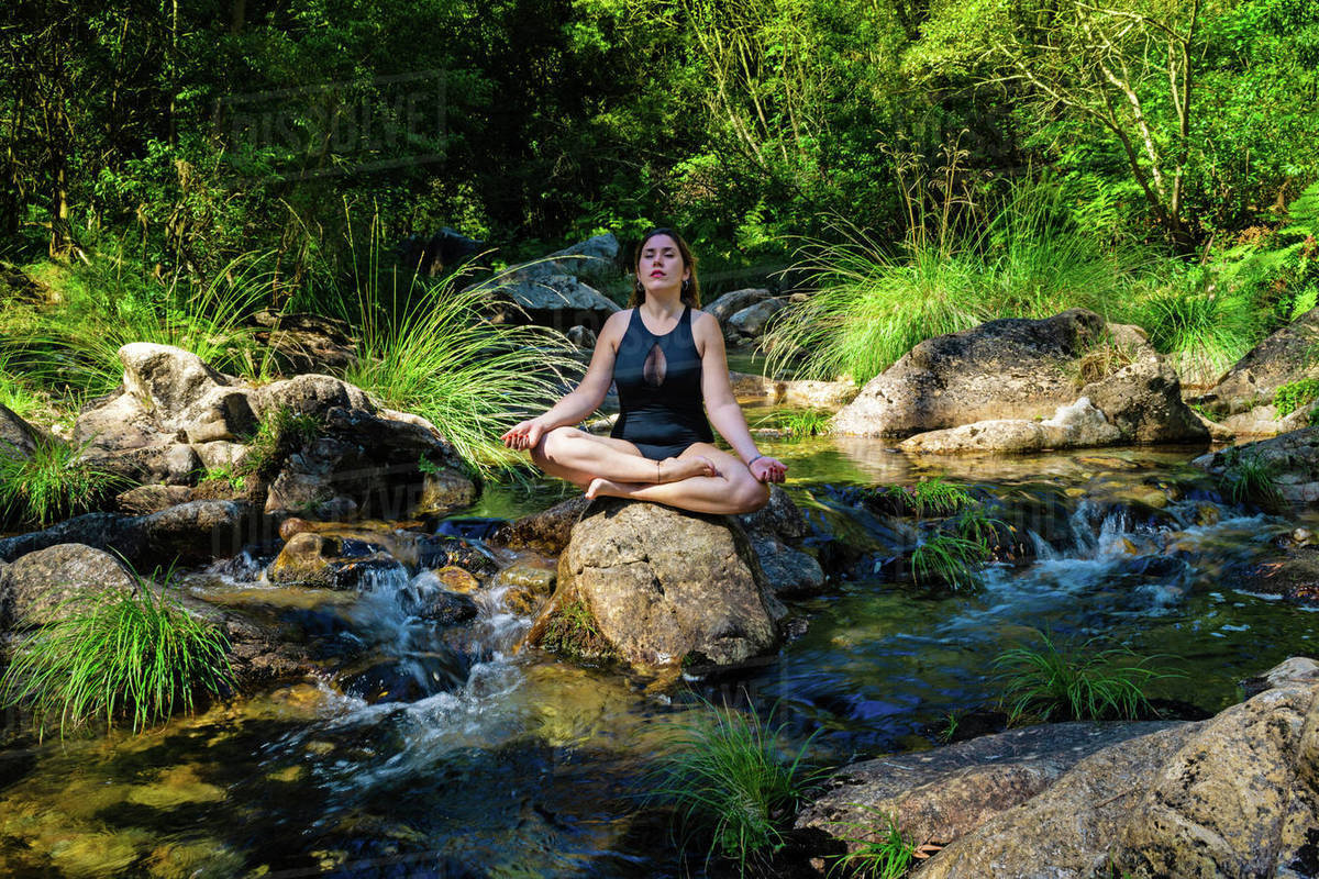 Young woman sitting in lotus pose on a rock in a river, Pozas de ...