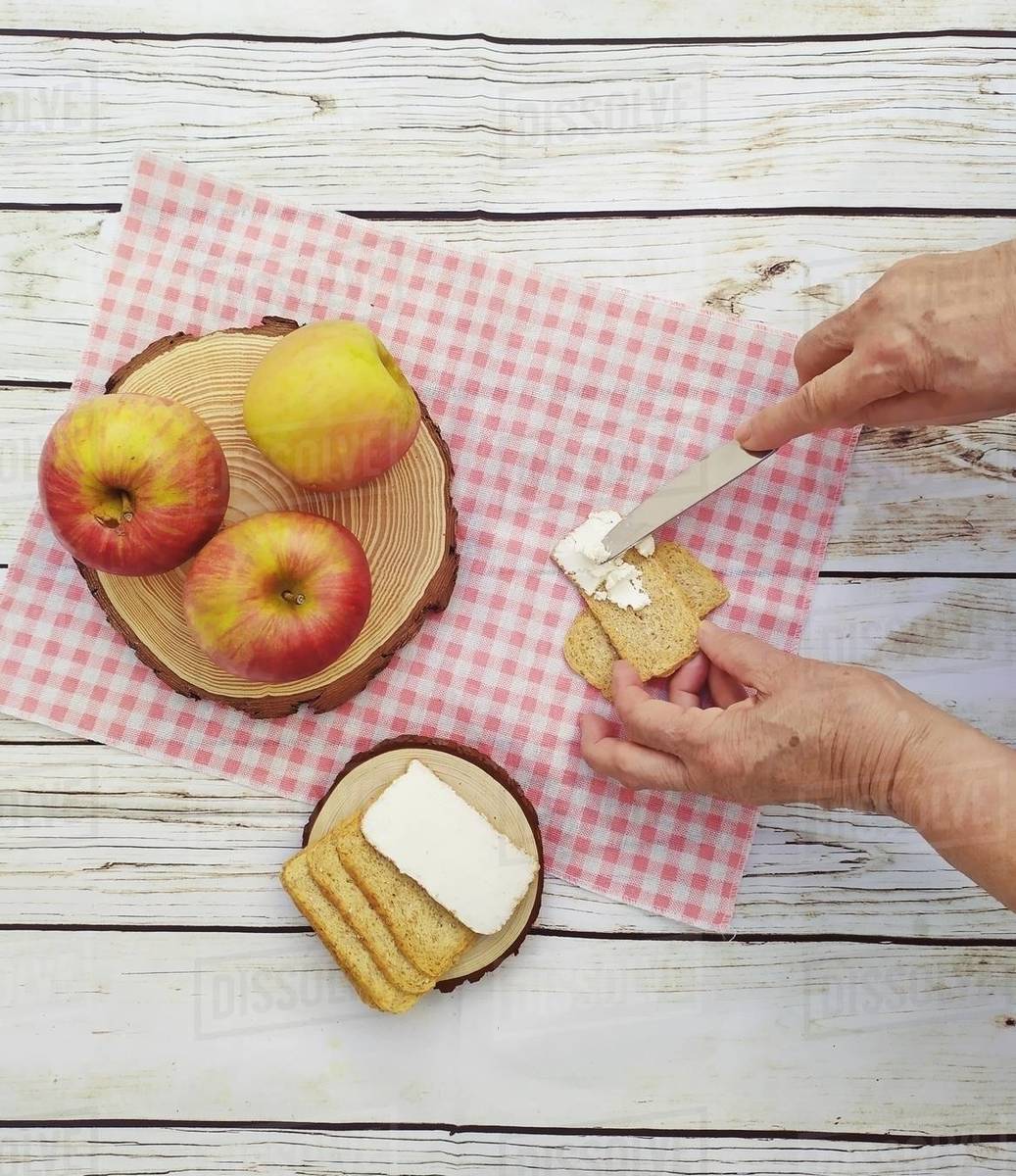 Overhead view of a person spreading cream cheese on a cracker with ...