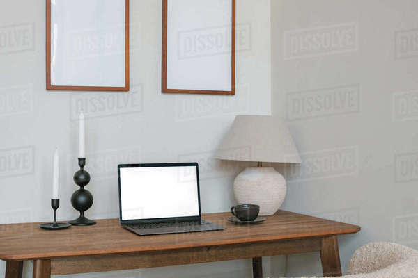 Open laptop with a blank screen, candlesticks and a lamp on a table ...