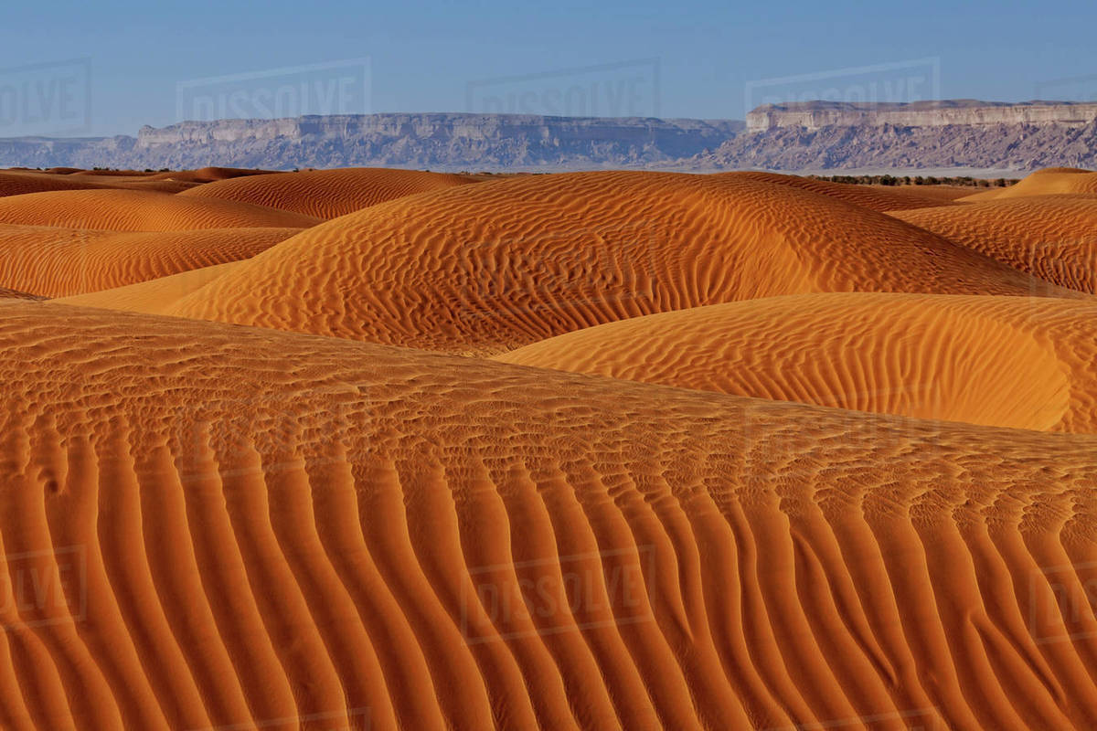 Desert landscape with ripped sand dunes with mountain backdrop, Saudi ...