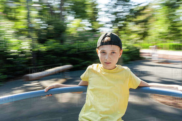 Boy spinning around on a carousel in a park in summer, Georgia - Stock ...