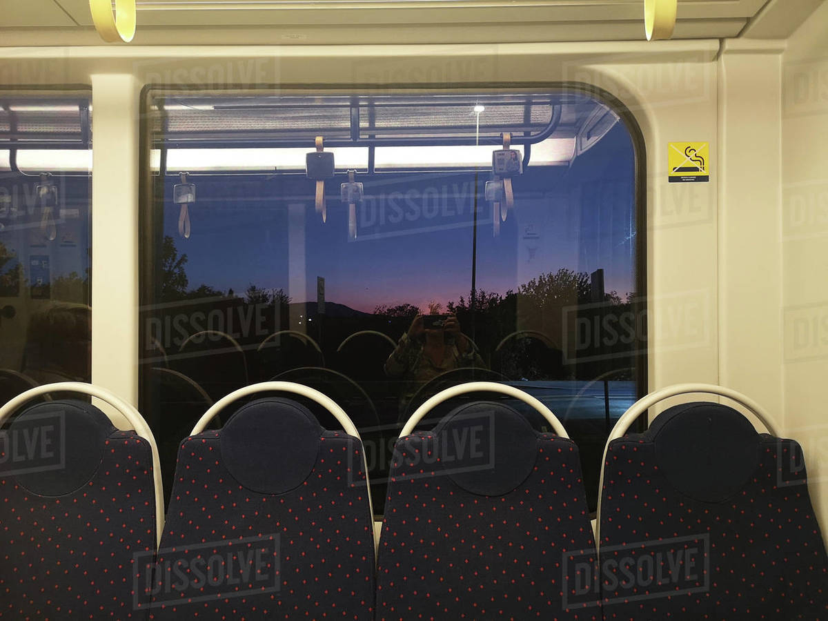 Reflection of a woman taking a photo of an empty metro at sunrise ...