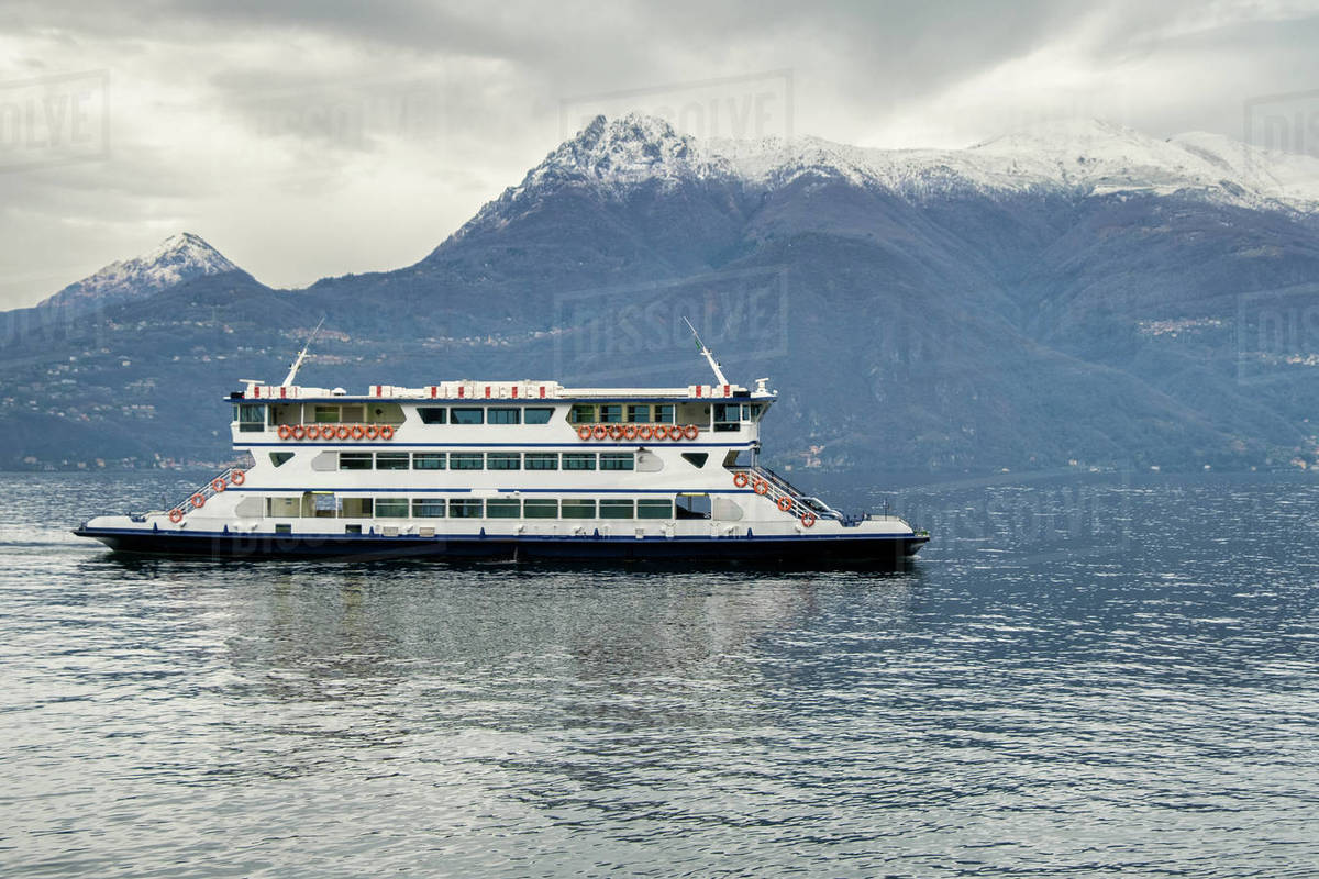Ferry boat sailing across Lake Como with mountain backdrop, Varenna ...