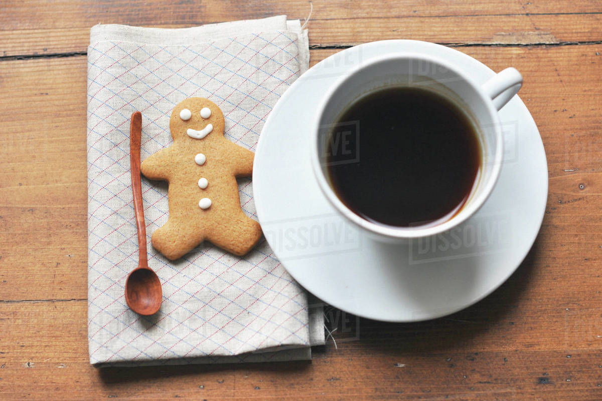 Cup of coffee and gingerbread man with spoon on wooden table - Royalty ...
