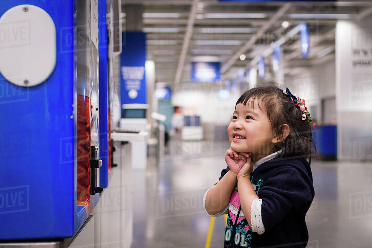 Girl standing by vending machine in corridor and smiling - Royalty-free ...