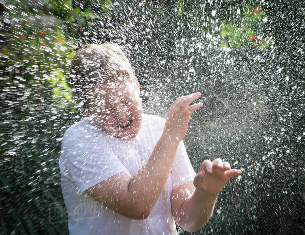 Boy being sprayed with water - Stock Photo - Dissolve
