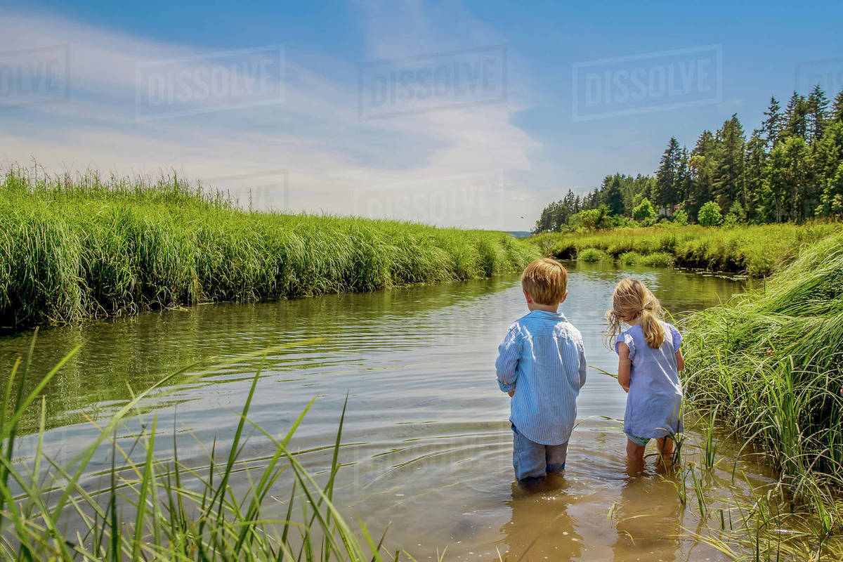 Boy and girl walking in river - Royalty-free Stock Photo | Dissolve