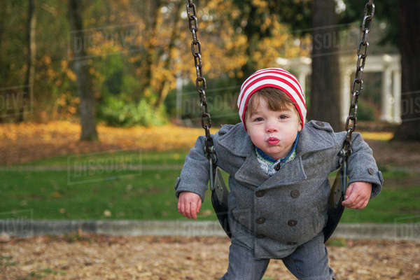 Boy on a swing puckering lips - Royalty-free Stock Photo | Dissolve