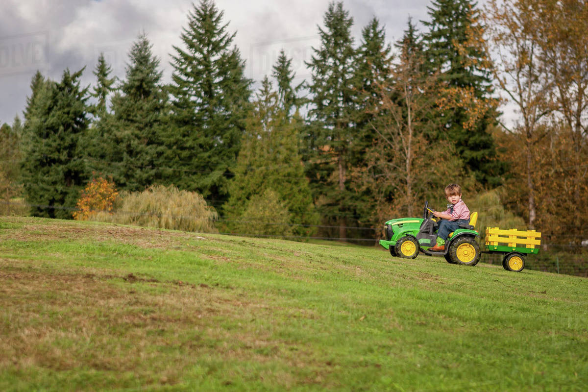 Boy driving a toy tractor up a hill - Royalty-free Stock Photo | Dissolve