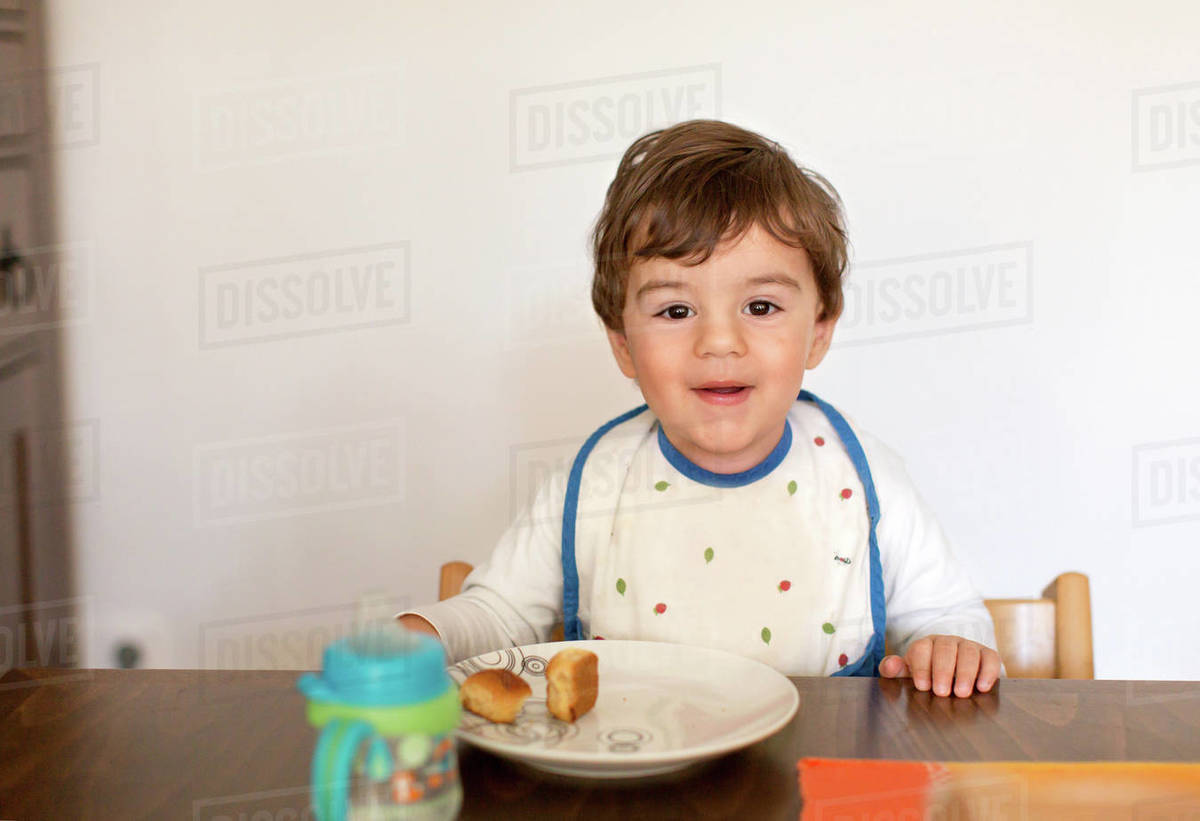 Smiling boy sitting at table eating snack - Royalty-free Stock Photo ...
