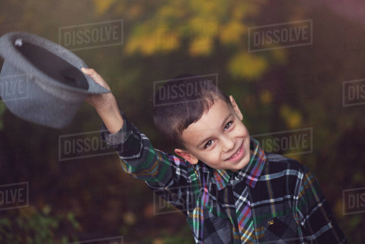 Smiling Boy taking off his hat - Stock Photo - Dissolve