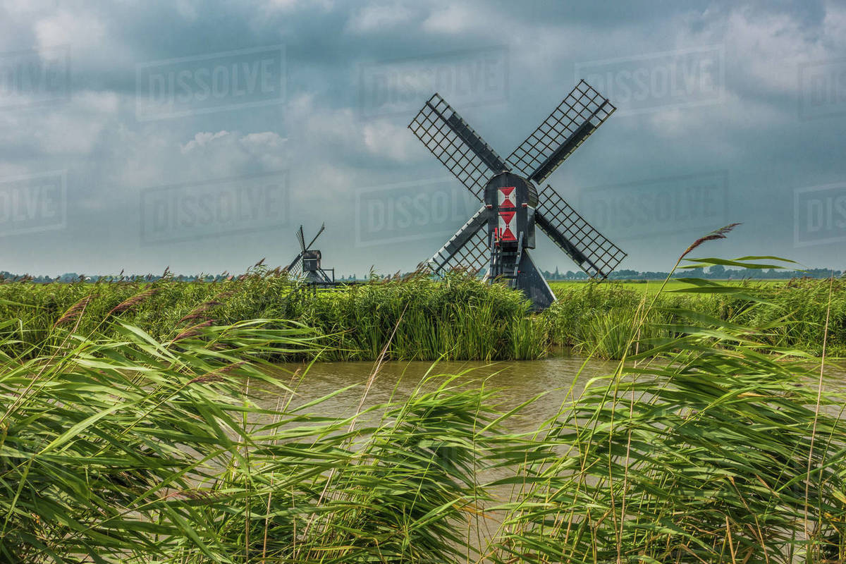 Windmills along riverbank, Friesland, Netherlands - Royalty-free Stock ...