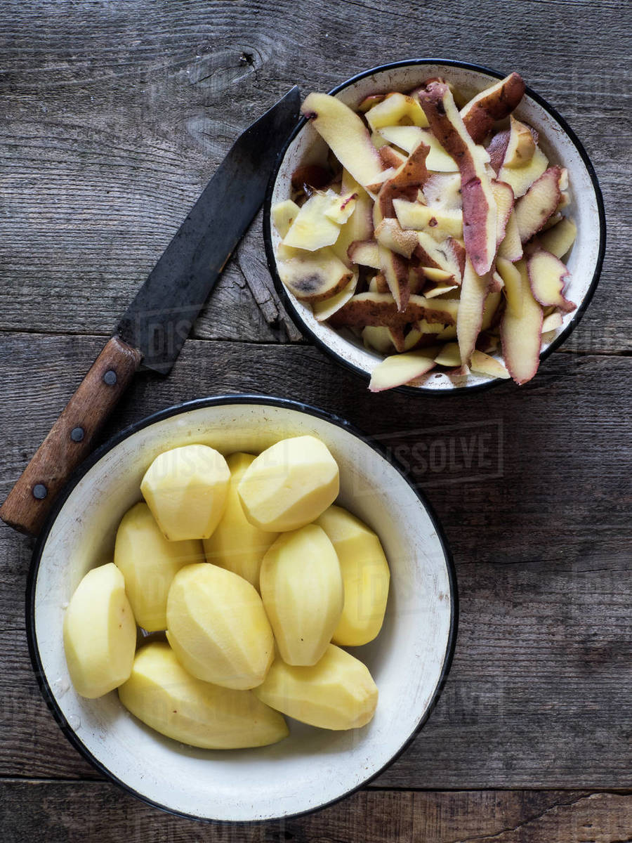 Peeled potatoes, potato peelings and knife on table - Royalty-free ...