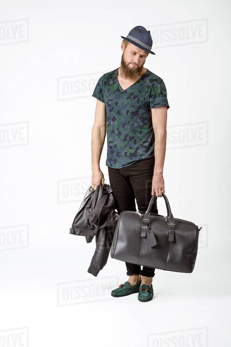 Hipster man holding jacket and bag - Royalty-free Stock Photo | Dissolve