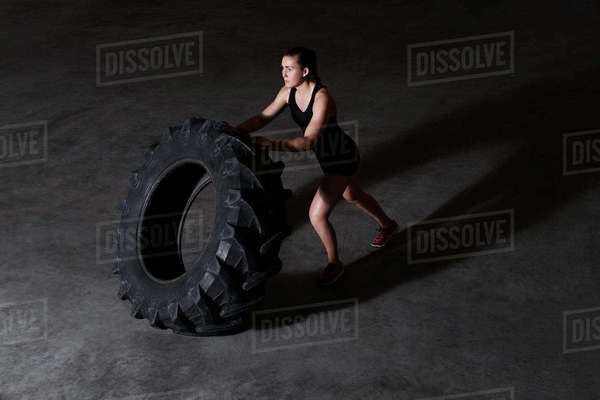 Woman pushing tractor tire in gym - Royalty-free Stock Photo | Dissolve