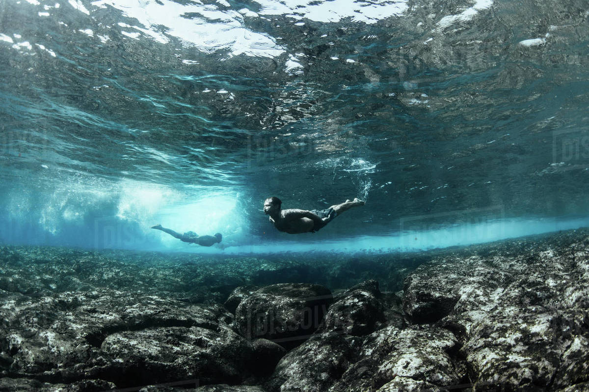 Two men swimming underwater in ocean, Kalapana, West Puna, Hawaii ...