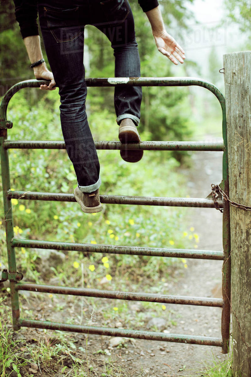 Man climbing over barrier - Stock Photo - Dissolve