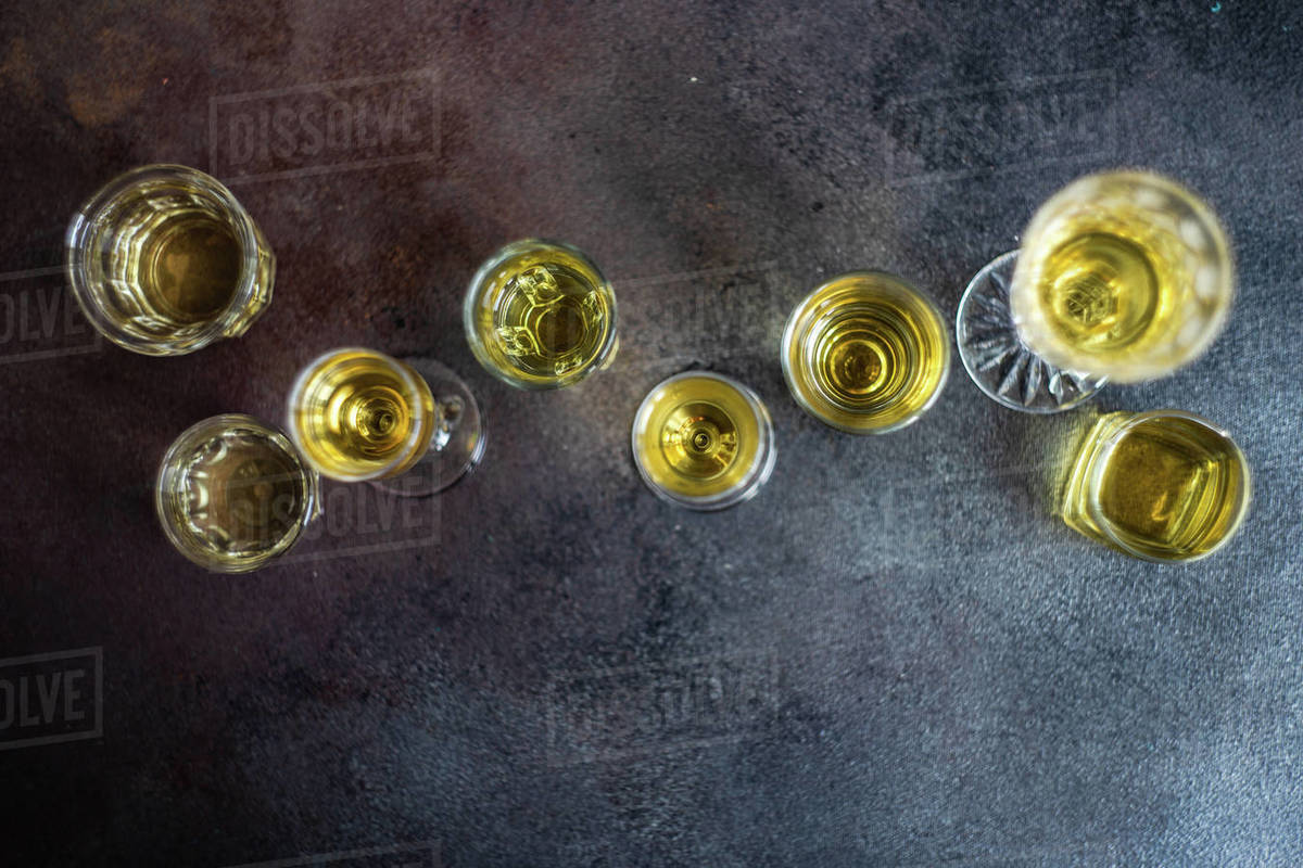 Row of assorted shot glasses, wine glasses and tumblers filled with ...