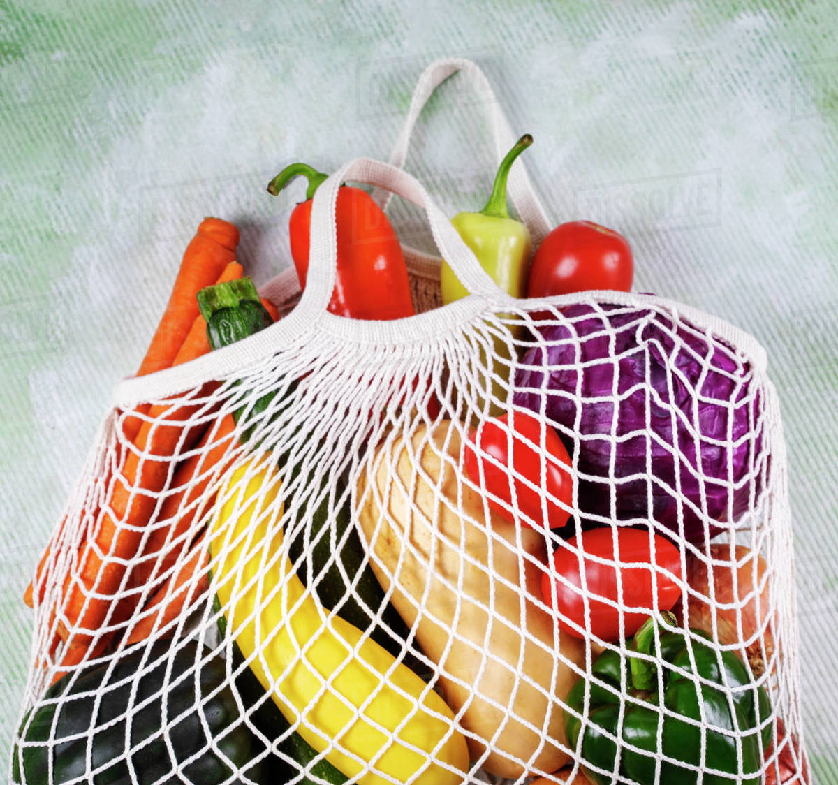 Reusable mesh bag with assorted fruit and vegetables on a table ...