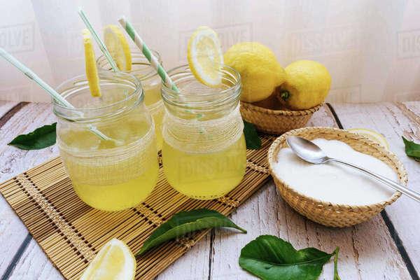 Three glasses of homemade lemonade on a table with fresh lemons and a ...