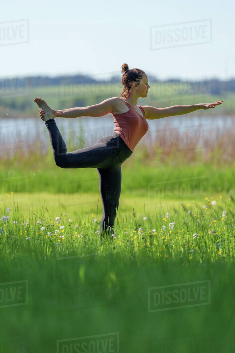 Woman standing on one leg doing dancer pose by Wallersee, Salzburg ...