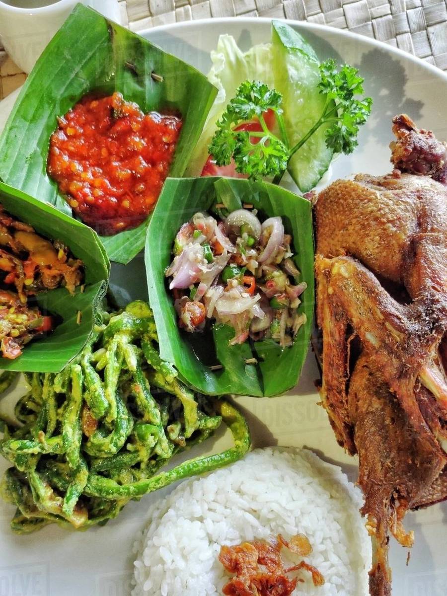 Overhead view of crispy duck with rice, chili sauce and vegetables ...