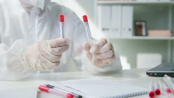 Marking PCR tests in laboratory, doctor writing results on COVID-19 ...