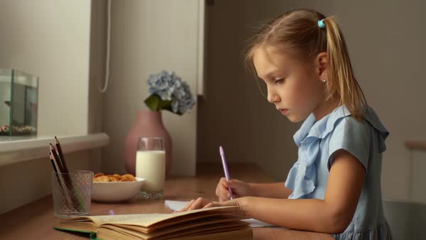 Close-up side view of concentrated primary child school girl writing to ...