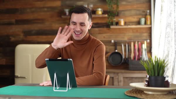 Handsome Caucasian young man using tablet computer having online video ...