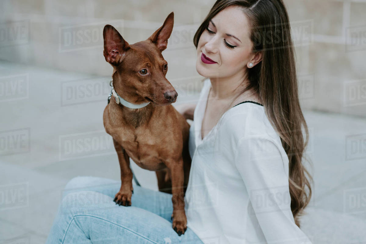 Beautiful casual woman with hound dog sitting on concrete step on ...