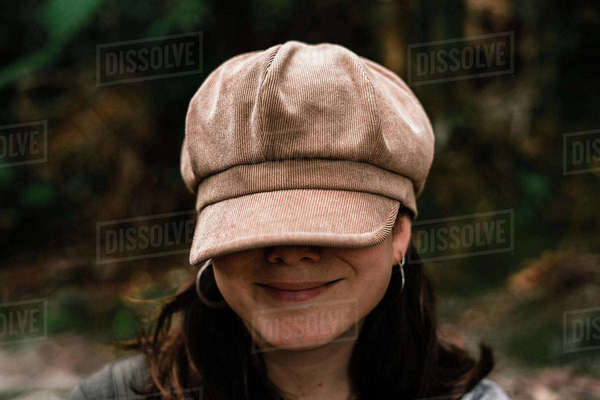 Content playful brunette wearing cap covering eyes and smiling on ...