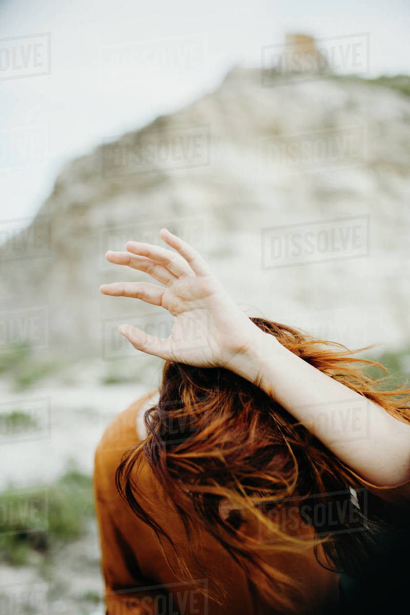 anonymous thoughtful female model in blouse holding hand above head on ...