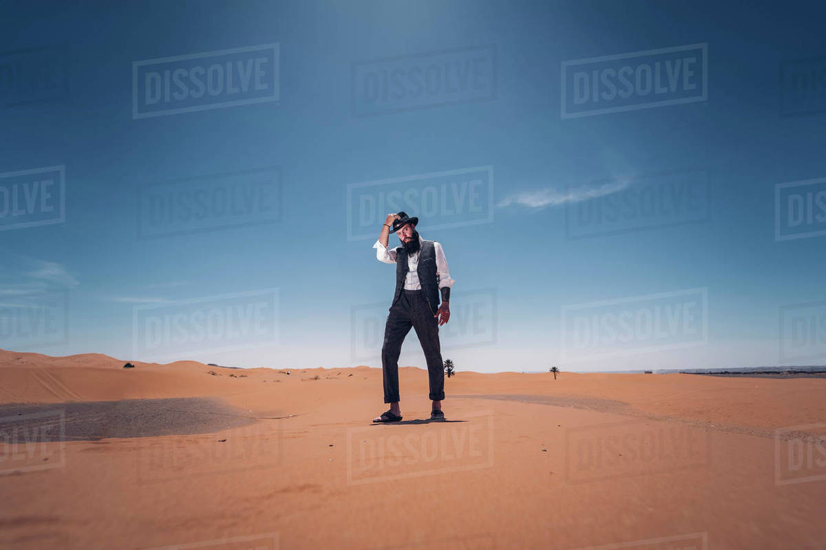 Bearded man in cowboy costume looking at camera while standing in ...