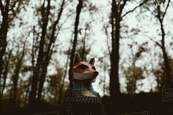 Anonymous female in paper fox mask walking in mysterious autumn forest ...