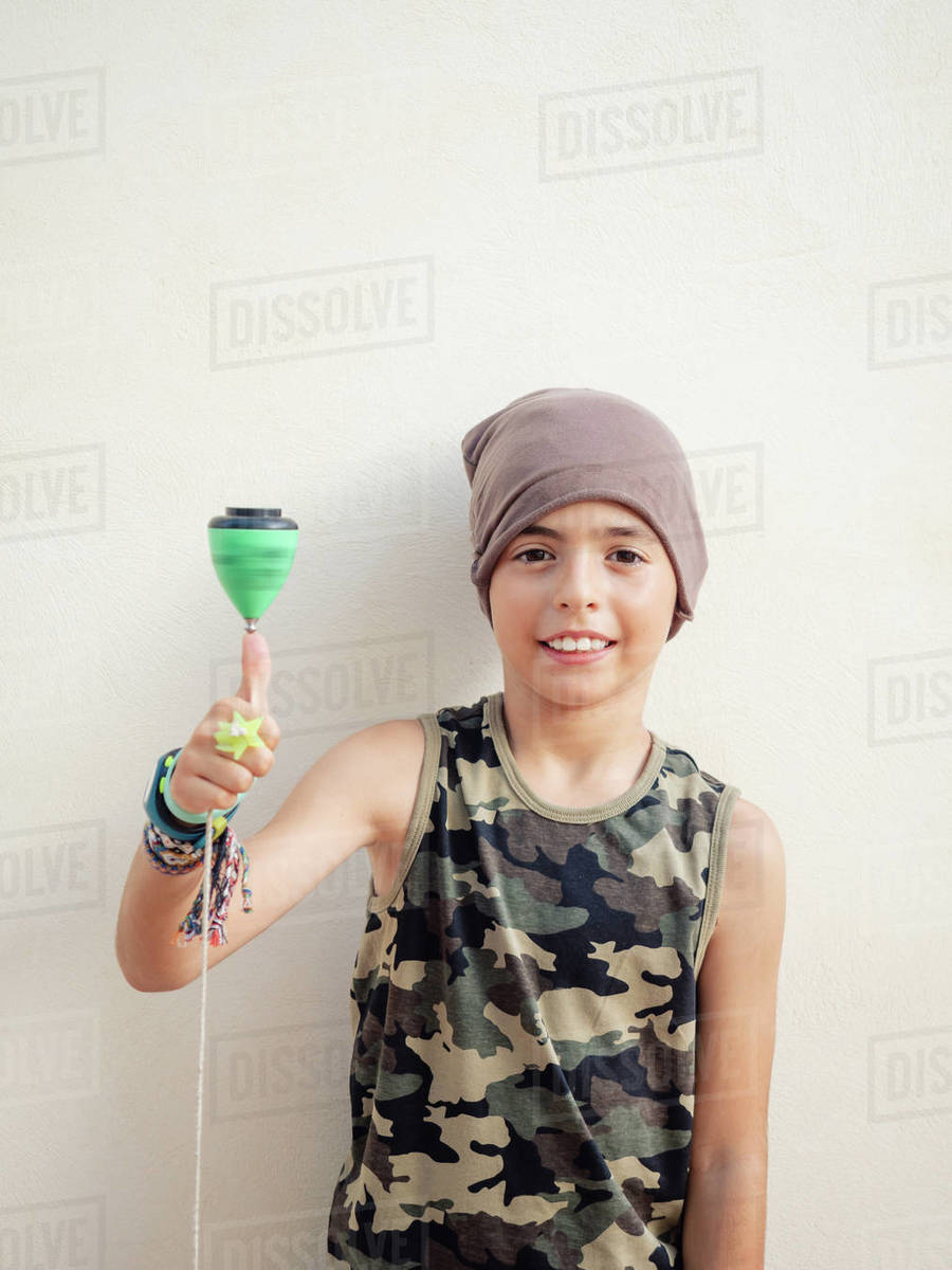Smart stylish boy in hat easily spinning green top while looking at ...