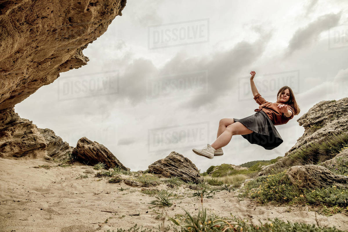 Beautiful young female floating in air above mountains in zero gravity ...