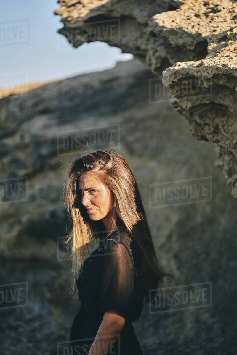 Young long haired stylish pensive female model looking down standing in ...