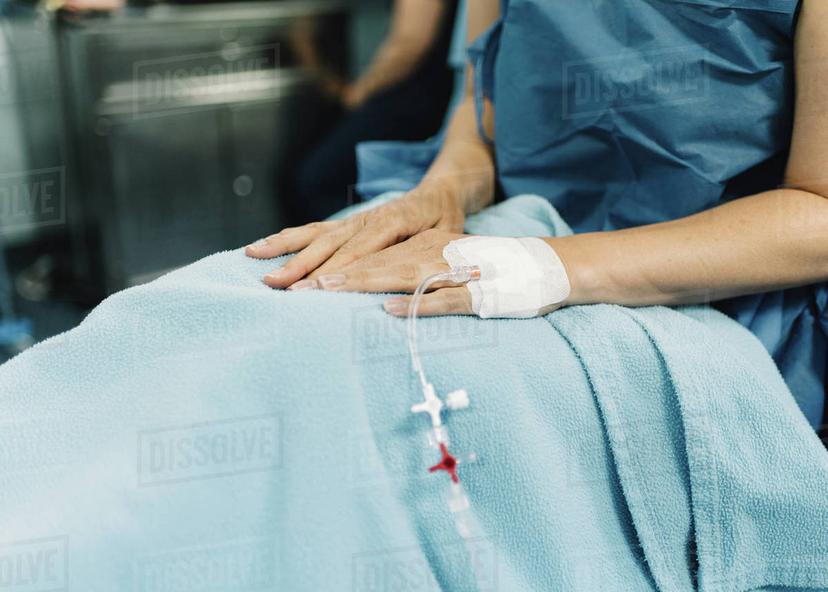Crop female patient sitting with covered legs and intravenous fluid ...
