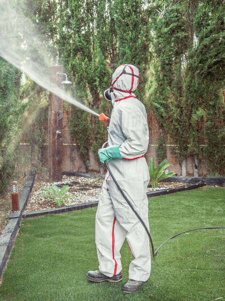 Fumigator in white uniform spraying substance on garden - Stock Photo ...