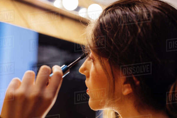 Side view of crop brunette attractive woman looking in mirror doing ...