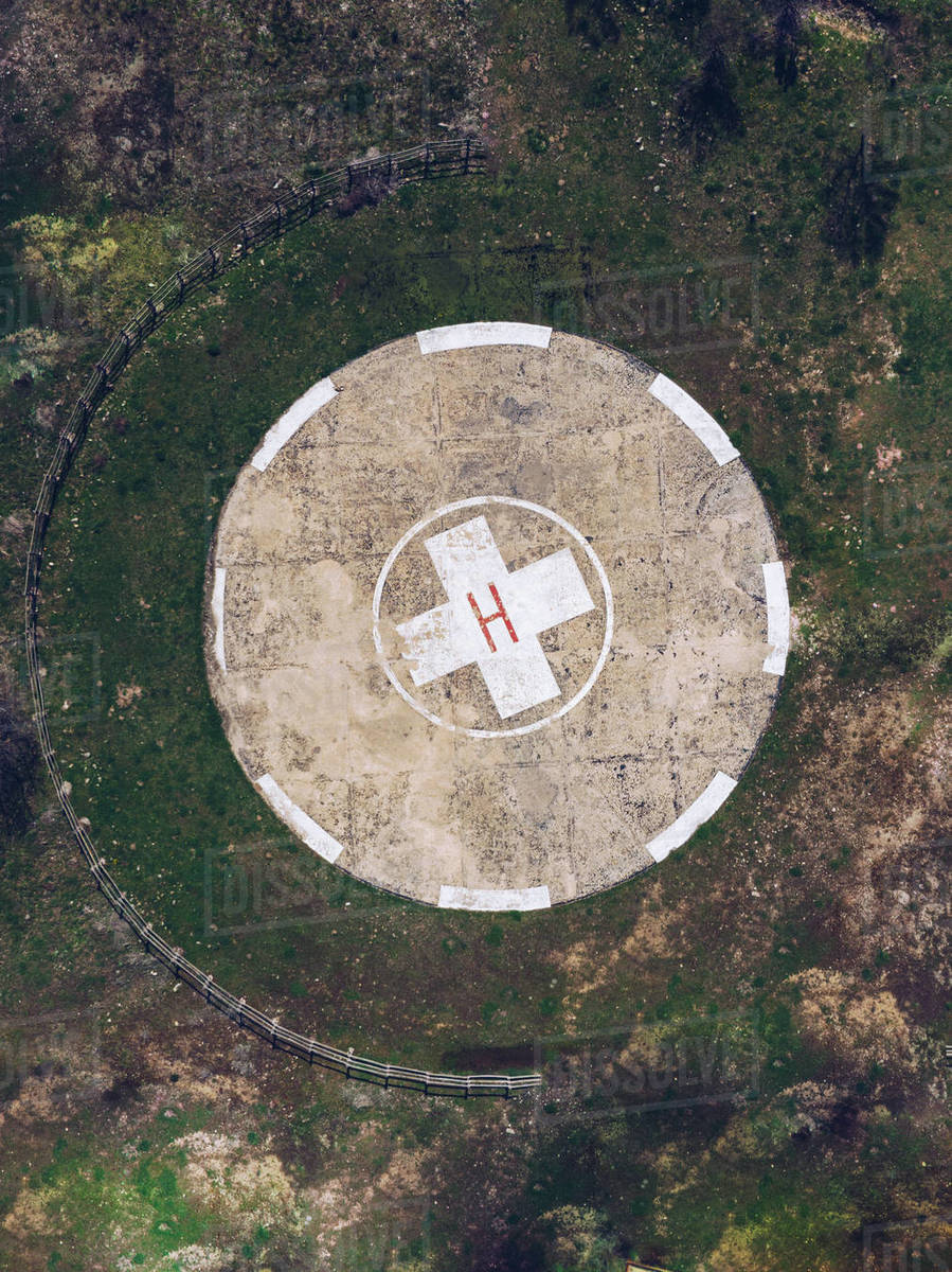 Drone top view of round concrete helipad on grassy rural valley on ...