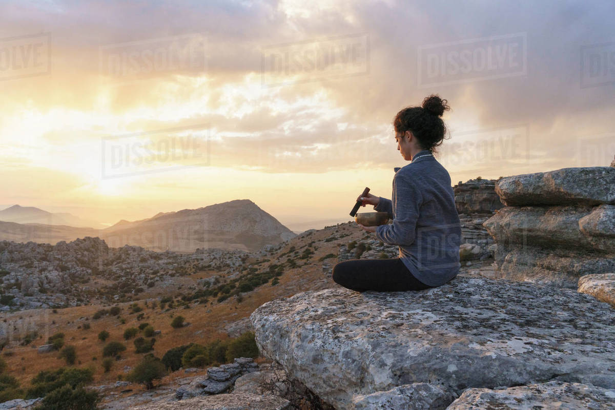 Full body side view of serene young female sitting in lotus pose with ...