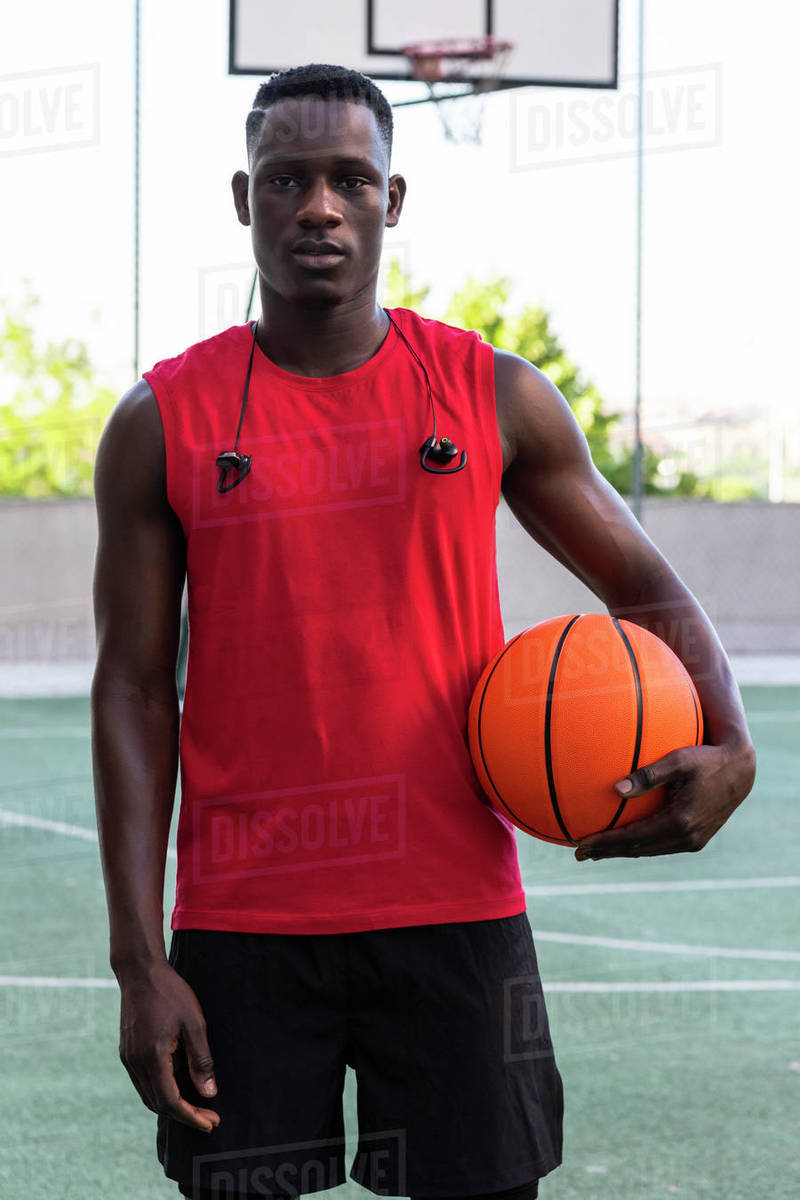 Determined male basketball player standing with ball on playground in ...