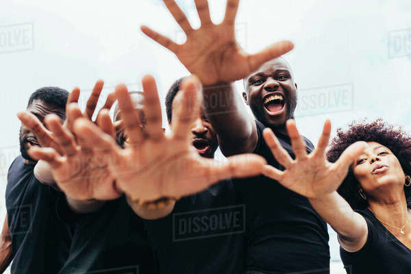 Cheerful black men and woman raising hands against a blue sky - Royalty ...